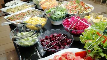 Buffet com diversas opções de comida, incluindo saladas, frutas e legumes.