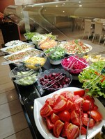 Buffet com diversas opções de comida, incluindo saladas, frutas e legumes.
