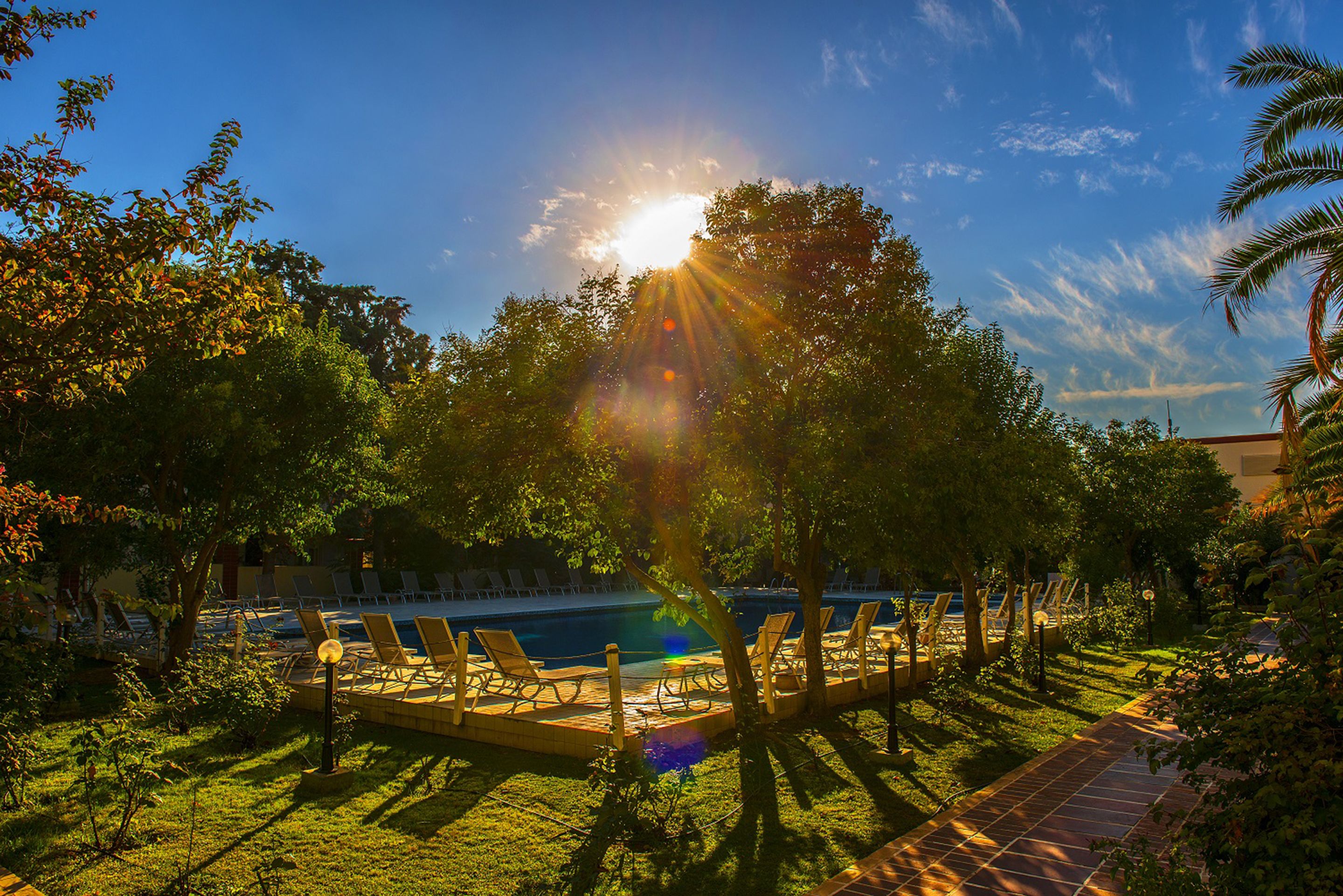 Área da piscina com espreguiçadeiras iluminadas pelo sol e vista desobstruída da piscina.