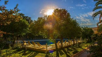 Área da piscina com espreguiçadeiras iluminadas pelo sol e vista desobstruída da piscina.