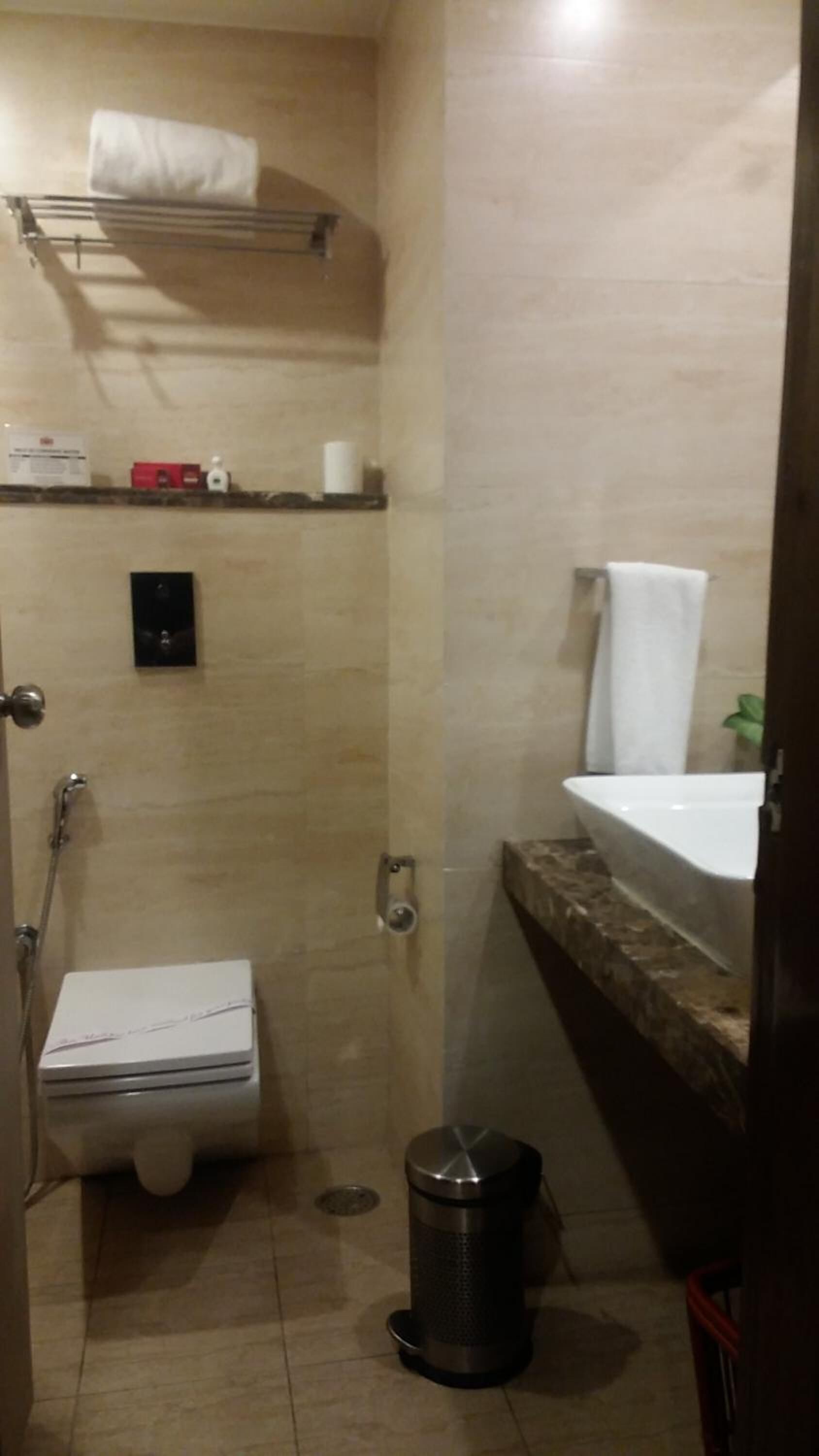 Uma casa de banho pequena com sanita, lavatório, caixote do lixo e chuveiro.
