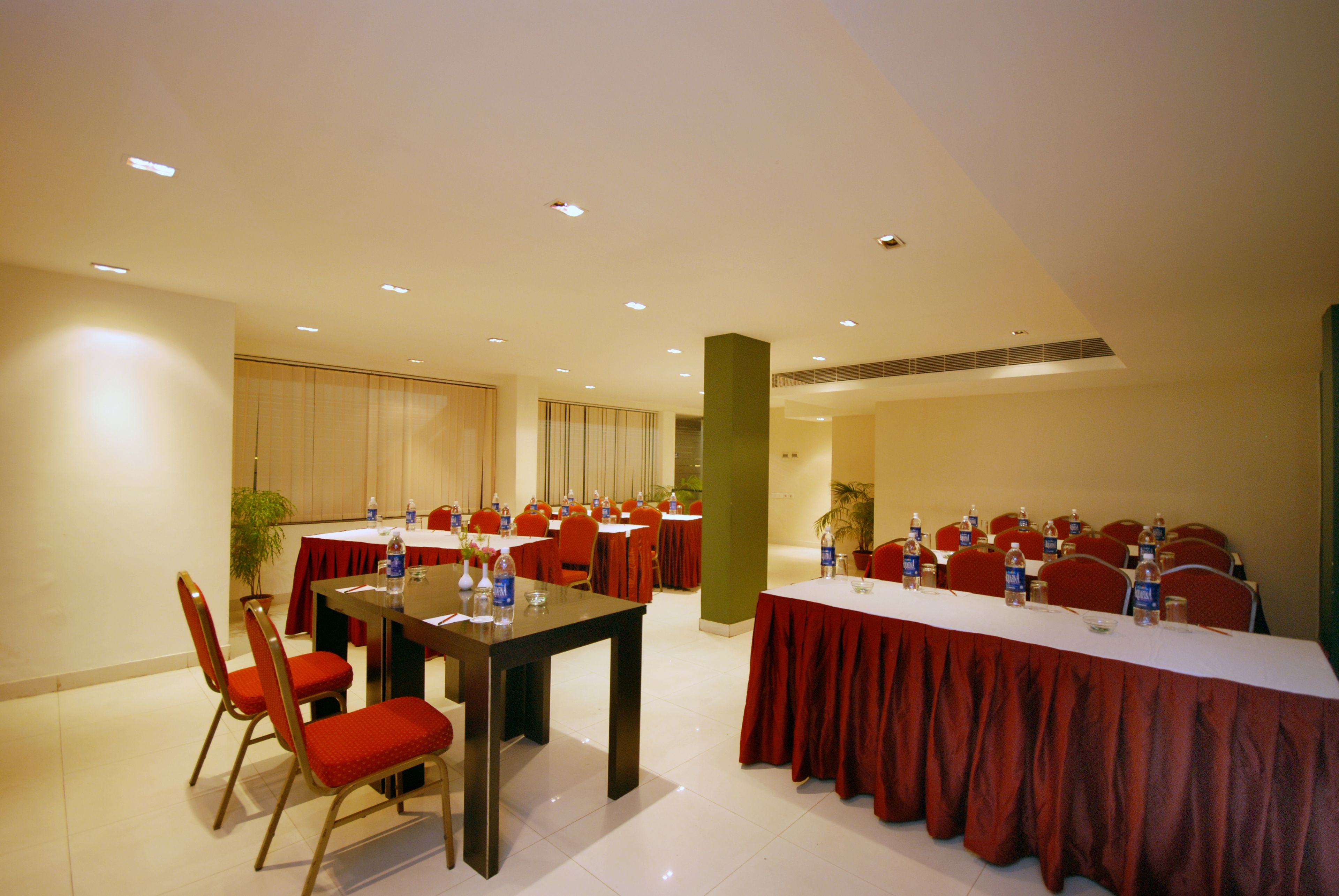 Uma sala de conferências com várias mesas, cadeiras e garrafas de água.