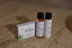 Uma caixa e duas embalagens de produtos MetroPole sobre uma superfície texturizada.