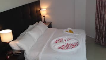 Quarto de hotel com cama bem arrumada, abajur, controle remoto e um copo de água na mesa de cabeceira.