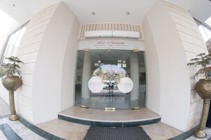 A entrada do La Maison Hotel & Spa, com design moderno, destacando uma fachada de vidro e uma entrada central.