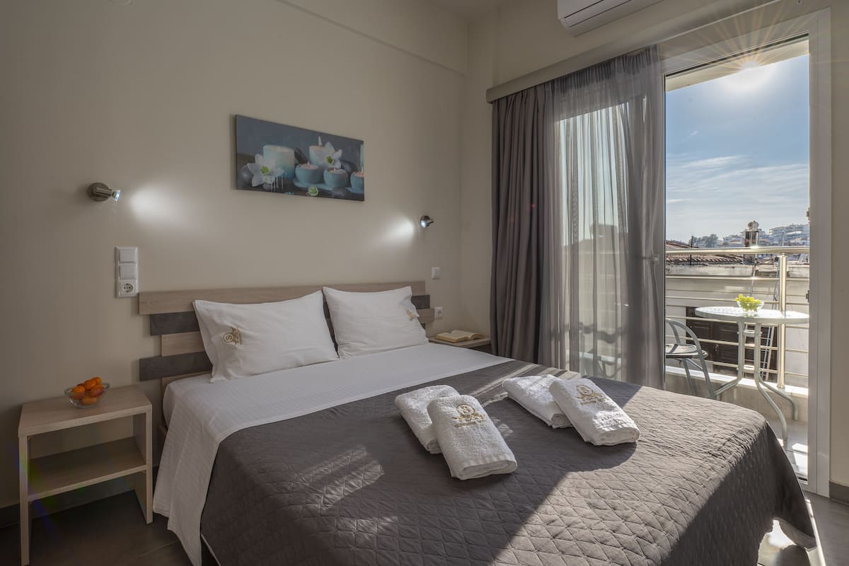 Quarto de hotel com cama, mesa de cabeceira, quadro e varanda com vista.
