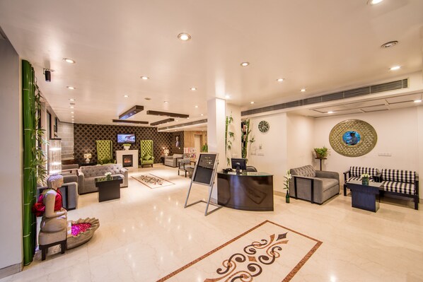 Um lobby moderno com balcão de recepção, sofás e uma parede decorativa.
