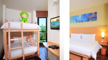 Quarto de hotel com beliche, uma escrivaninha com um laptop, um urso de pelúcia e uma televisão.