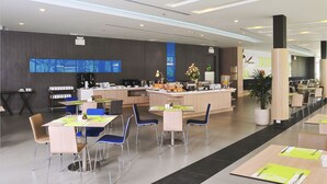Um restaurante moderno com ilha central, várias áreas de estar e cozinha ao fundo.