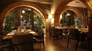 Um restaurante com arcos de tijolo, mesas e cadeiras de madeira.