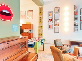 Um quarto acolhedor com cômoda de madeira, mesa de pebolim e uma cadeira confortável.