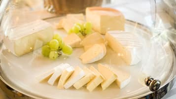 Exposição de queijo e uvas sobre uma mesa com cobertura de vidro.