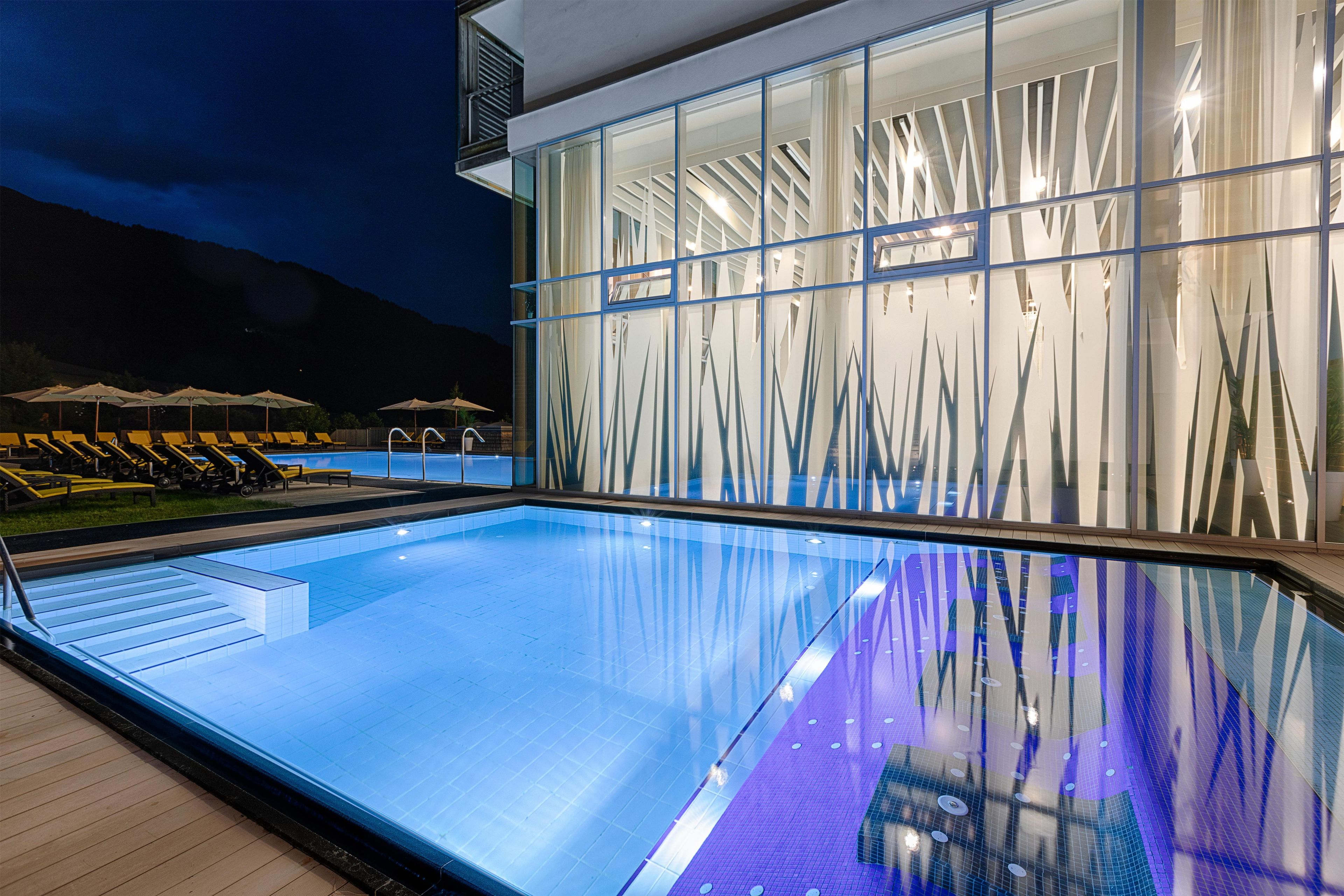 Piscina com barreira de vidro, espreguiçadeiras e guarda-sóis.