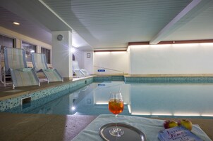 Uma área de piscina com espreguiçadeiras, um copo de bebida e um livro sobre uma toalha.