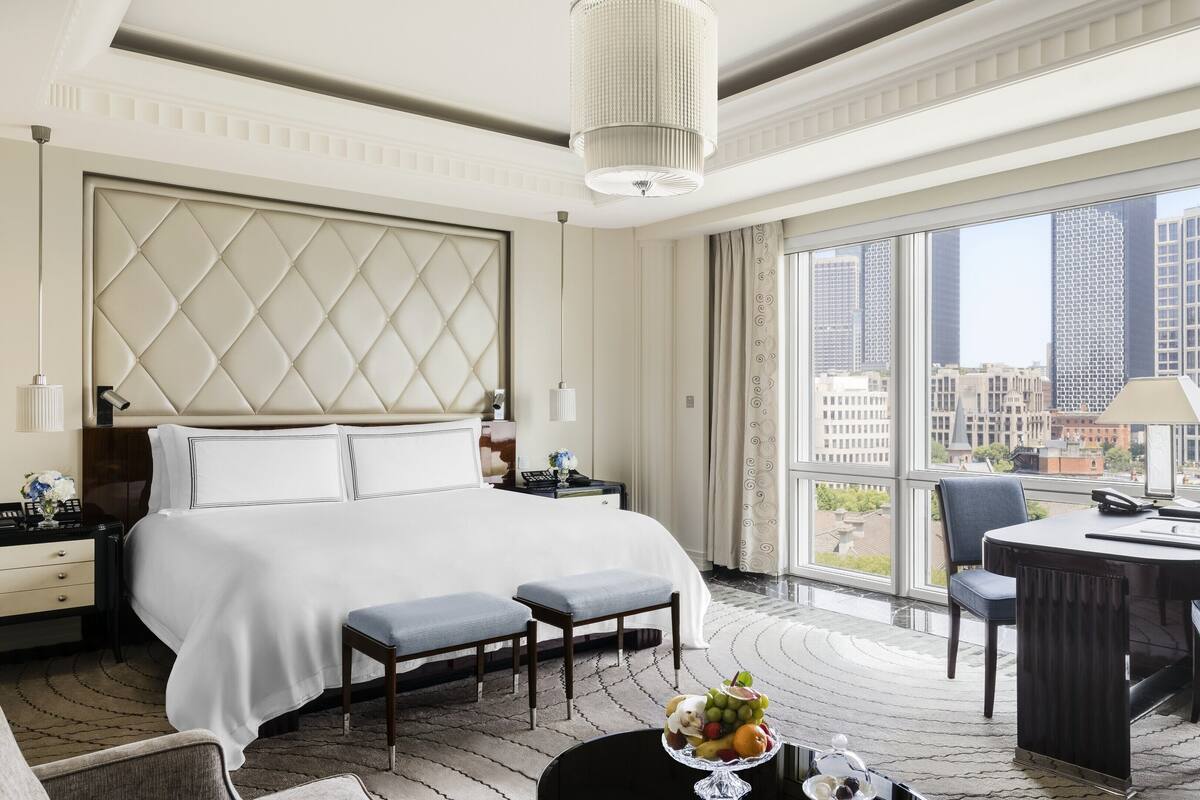 Quarto de hotel com cama grande, escrivaninha e vista para a cidade.