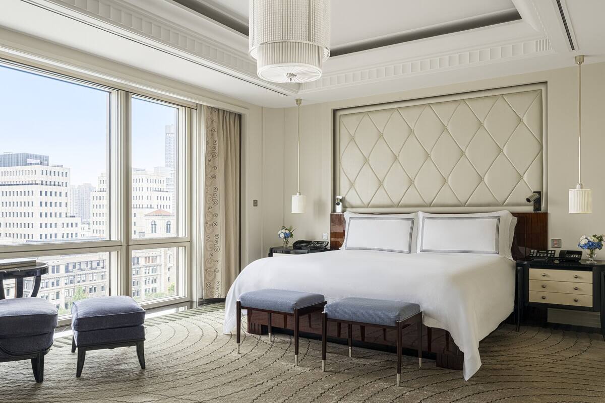 Quarto de hotel com uma cama grande, uma escrivaninha, uma cadeira e vista para a cidade.