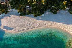 Na praia, espreguiçadeiras, guarda-sóis, toalhas de praia 