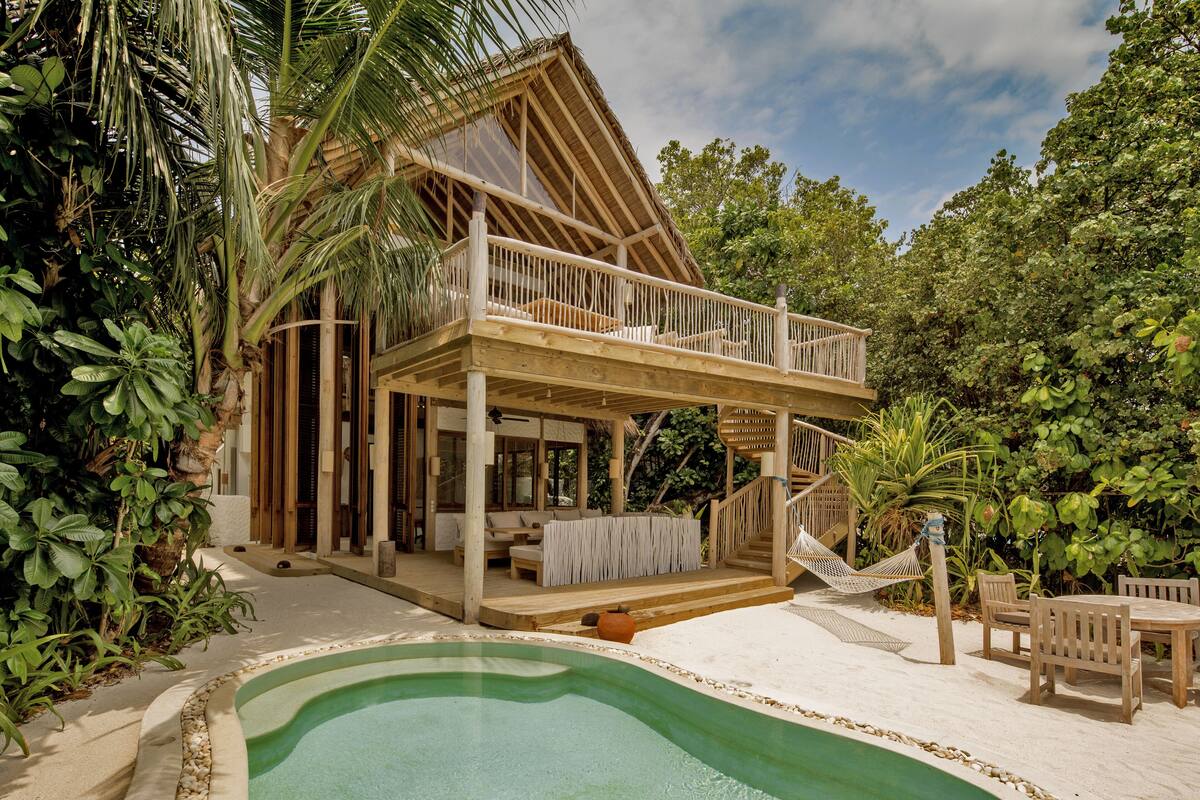 Uma casa de madeira com varanda, piscina e mobiliário de exterior.