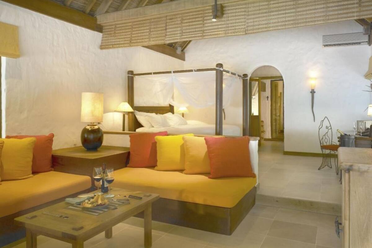 Quarto com cama de dossel, sofá, mesa de centro e área de refeições com uma cadeira e mesa.