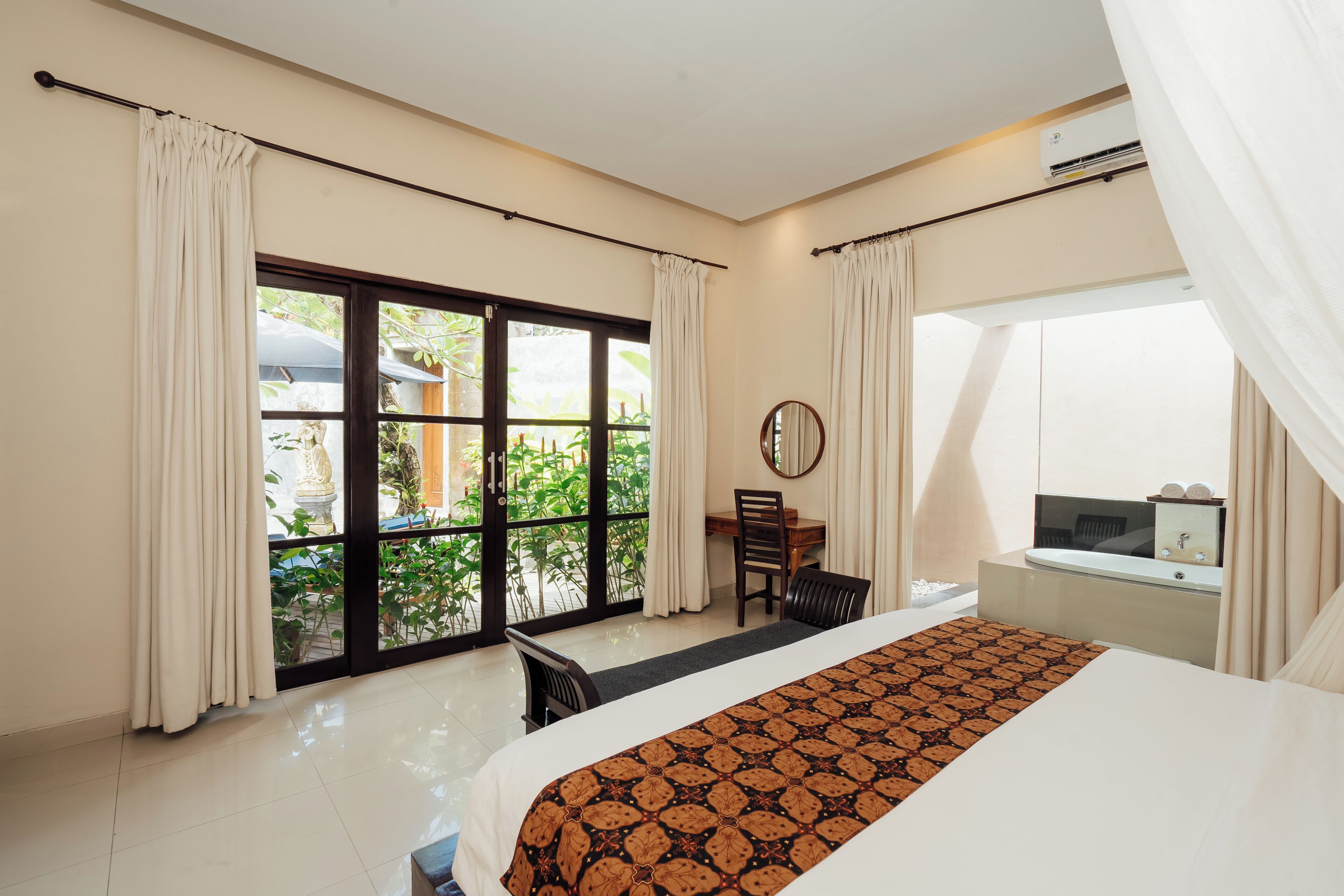 Quarto de hotel com uma cama grande, uma escrivaninha, uma cadeira e uma janela com cortinas.