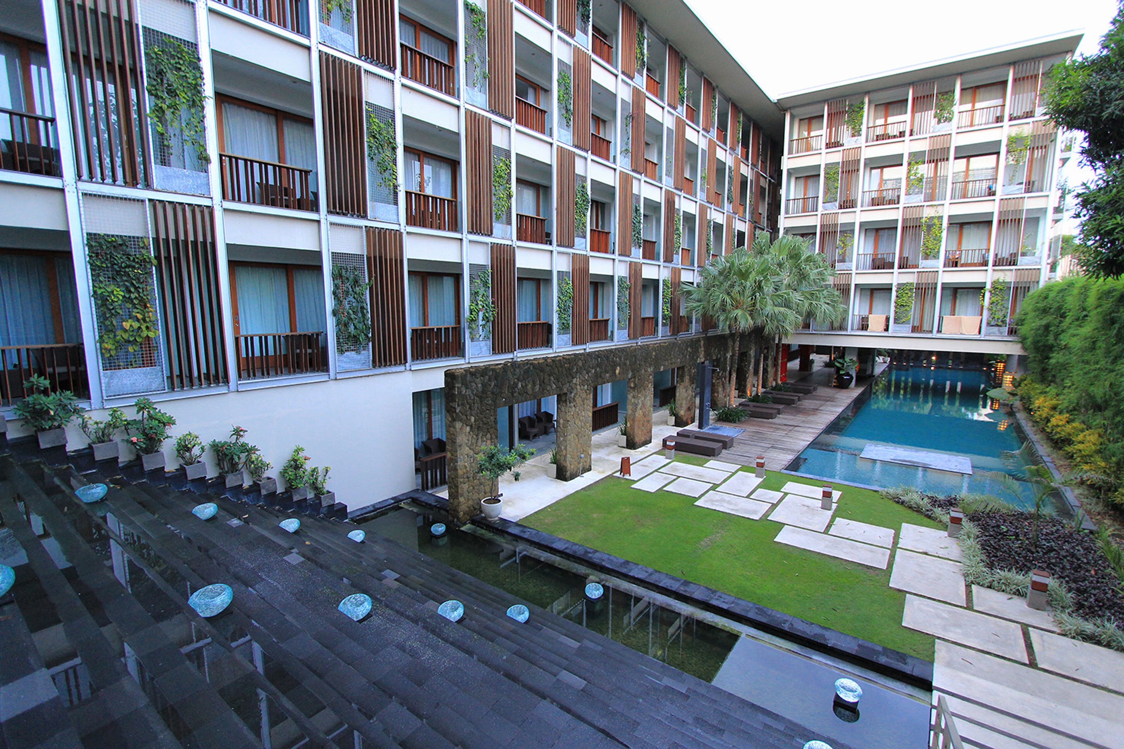 Um hotel com várias varandas, piscina e um pátio com gramado e área de estar.
