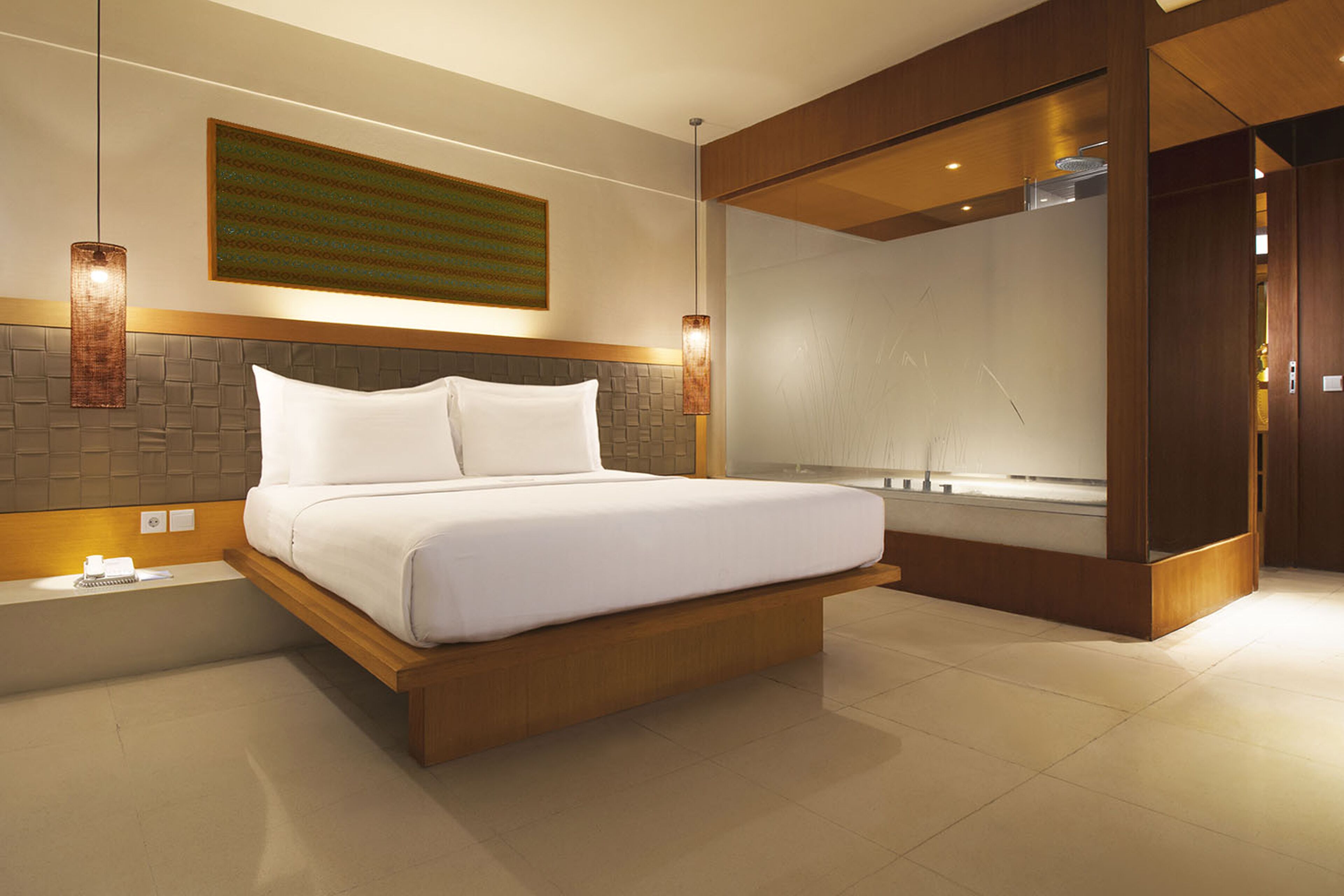 Quarto de hotel moderno com uma cama grande, chuveiro integrado e um espelho amplo.