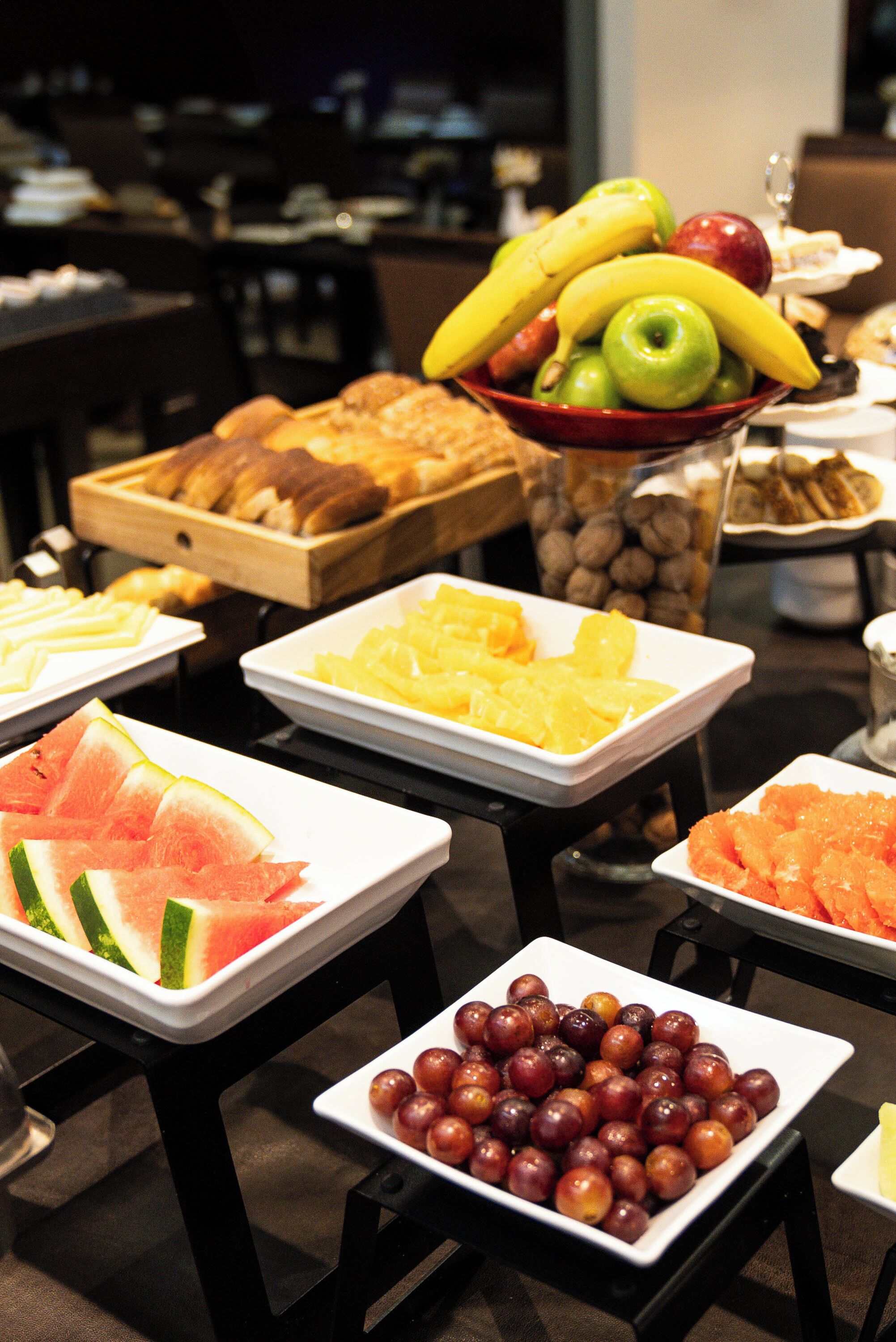 Buffet com diversas frutas, queijos e pães.