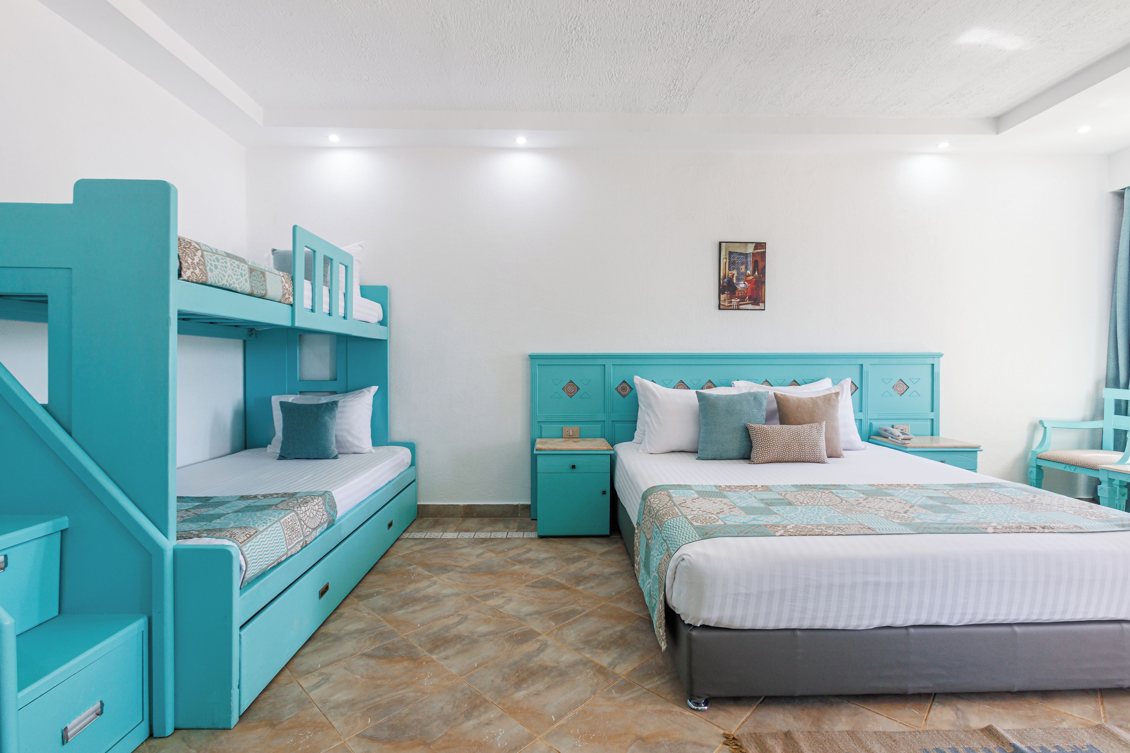 Quarto com beliches, uma cama de solteiro e uma mesa de cabeceira.
