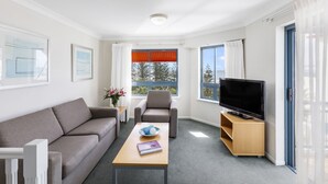 Uma sala de estar moderna com sofá, poltrona, mesa de centro e televisão.