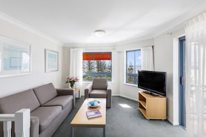 Uma sala de estar moderna com sofá, poltrona, mesa de centro e televisão.