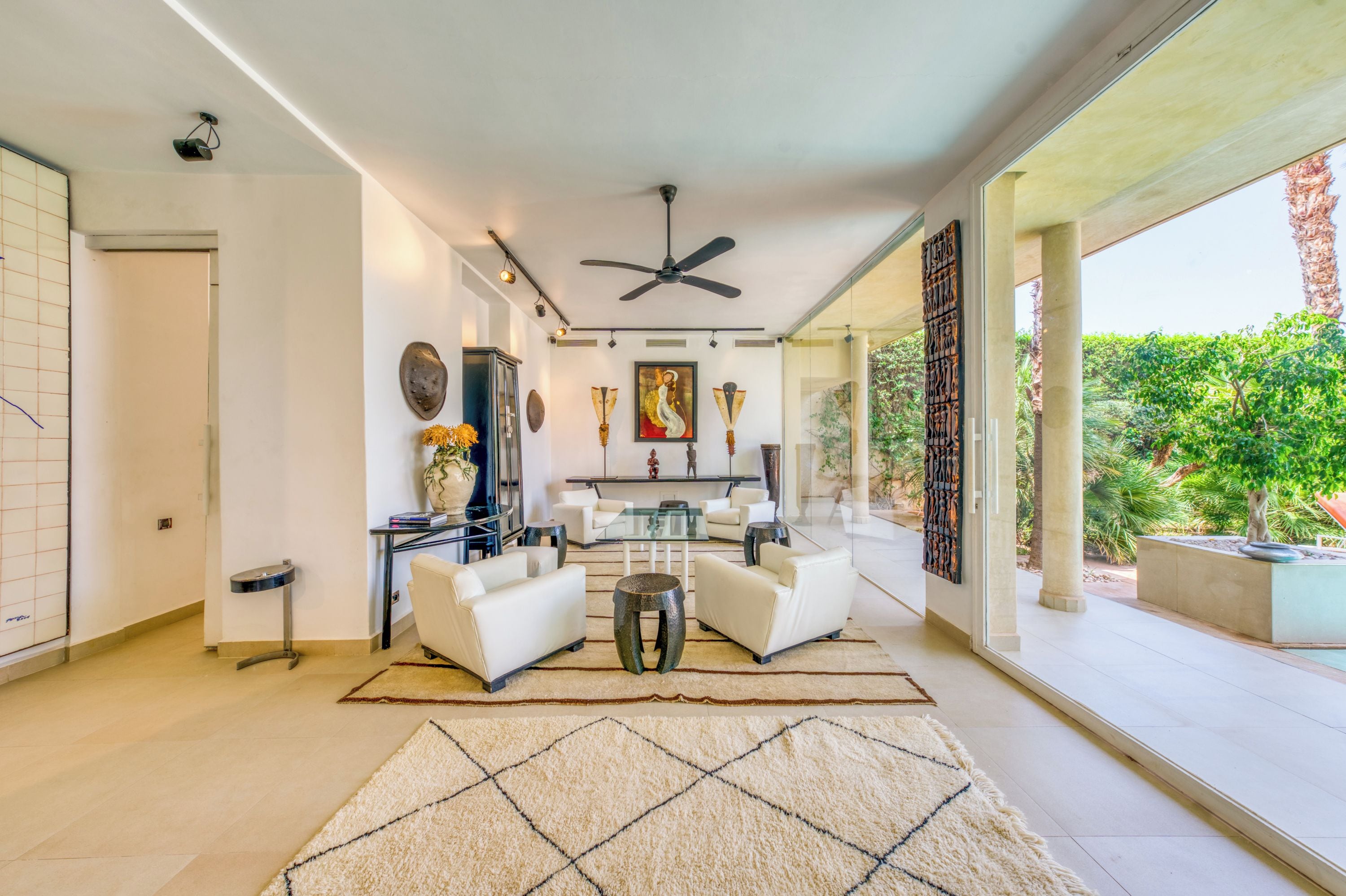 Uma sala de estar espaçosa com ventilador de teto, mesa de centro de vidro e sofá.