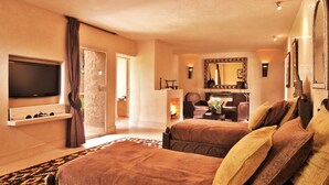 Quarto de hotel com duas camas, televisão, lareira e um espelho grande.