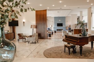 Uma sala de estar ampla com um piano, assentos confortáveis, uma TV e uma lareira.