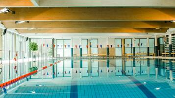 Piscina interior com pistas demarcadas, sinalização de segurança e design arquitetônico moderno.