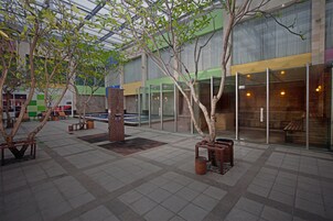 Um pátio interno com piso de azulejos, áreas de estar e um espaço envidraçado com um banco.
