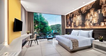 Quarto de hotel moderno com uma cama grande, uma escrivaninha e uma televisão.