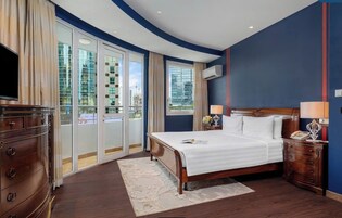 Quarto de hotel com uma cama grande, cômoda, mesa de cabeceira e televisão.