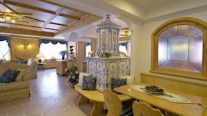 Um interior tradicional com teto de madeira, uma fonte decorativa central e uma área de refeições com mesa e cadeiras.