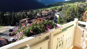 Varanda com vista para uma aldeia montanhosa, incluindo casas e vegetação.