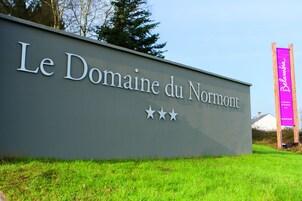 Um sinal para Le Domaine du Normont com três estrelas e um pequeno edifício ao fundo.