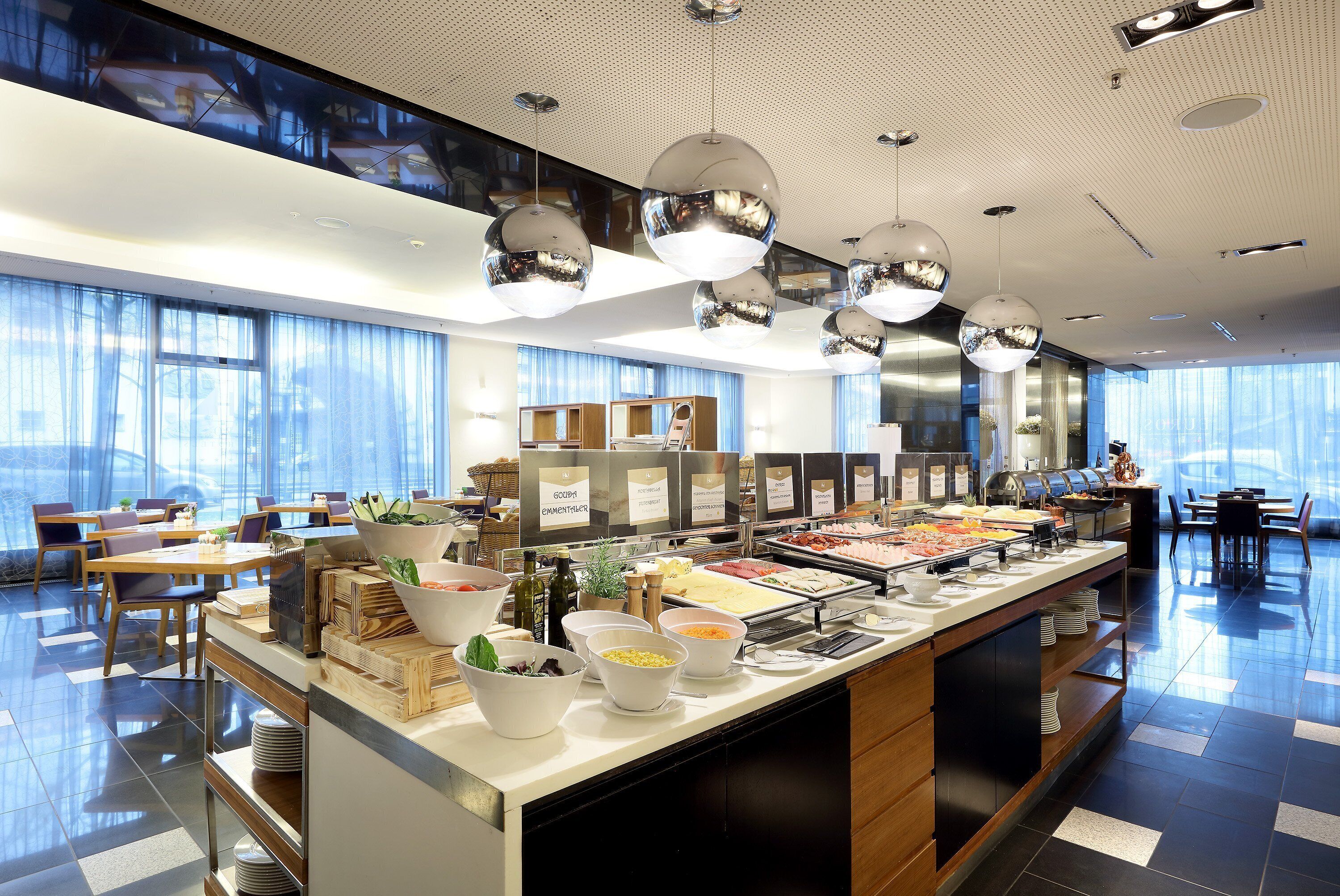 Uma área de buffet com diversos alimentos e um espaço de refeições com mesas e cadeiras.