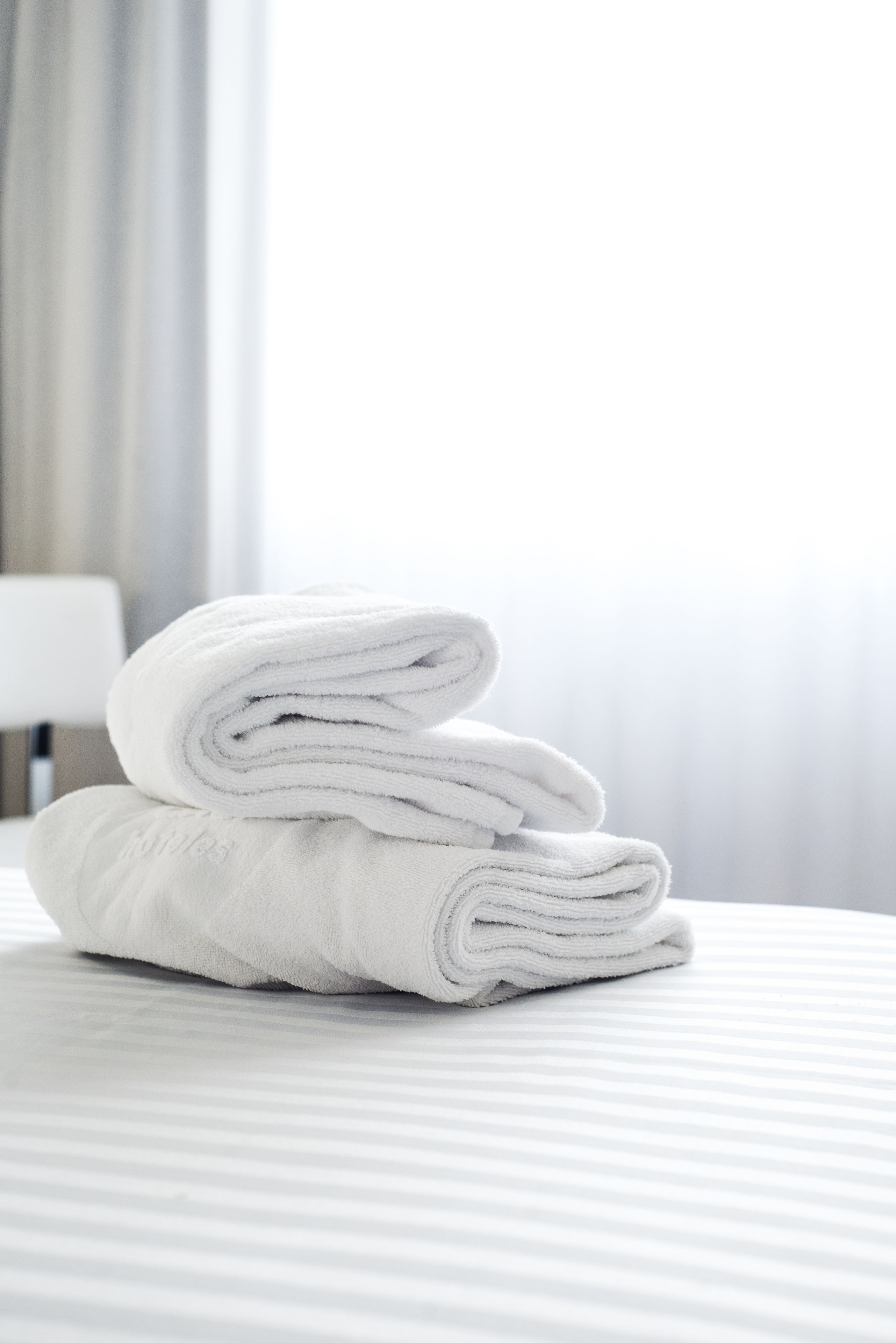 Uma pilha de toalhas brancas sobre uma cama com padrão listrado.