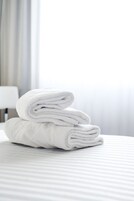 Uma pilha de toalhas brancas sobre uma cama com padrão listrado.