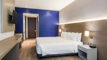 Quarto de hotel moderno com uma cama grande, uma escrivaninha e uma TV na parede.