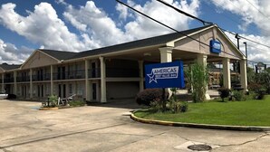 Um motel de dois andares com varanda coberta e placa indicando ser o Americas Best Value Inn.