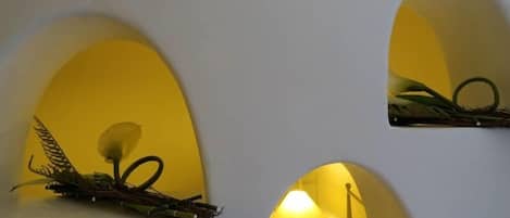 Três nichos fixos na parede com detalhes decorativos e uma luminária.