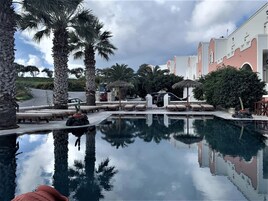 Uma área de piscina com espreguiçadeiras e palmeiras.