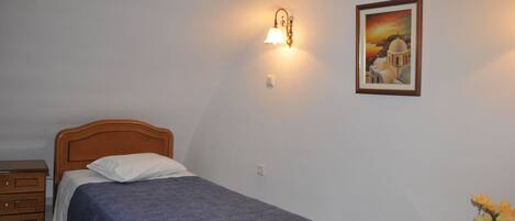 Quarto com cama de madeira, mesa de cabeceira, luminária na parede e uma pintura.