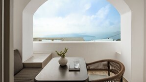 Varanda com vista para o mar, uma cadeira de vime, uma mesa pequena com um vaso e um copo, e um travesseiro.