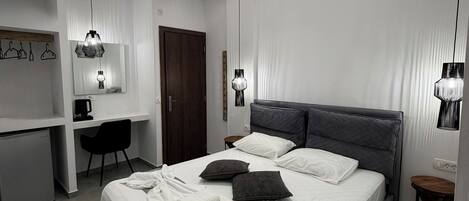 Quarto moderno com uma cama grande, mesas de cabeceira, escrivaninha e uma cadeira.